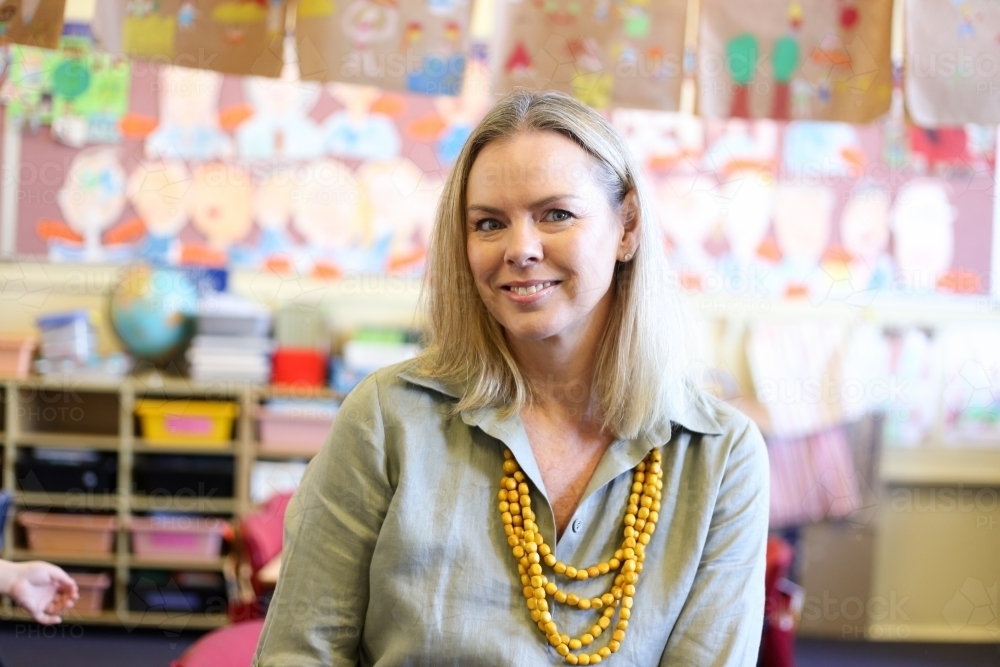 Image of Female teacher sitting in school classroom - Austockphoto
