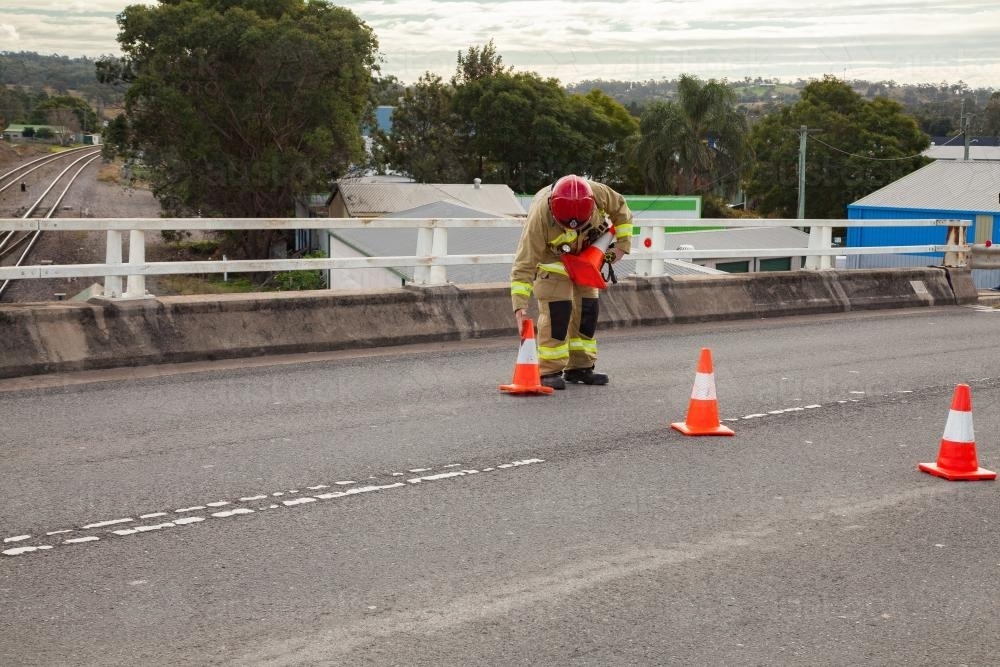 Image of Firefighter setting up road cones for a roadblock - Austockphoto