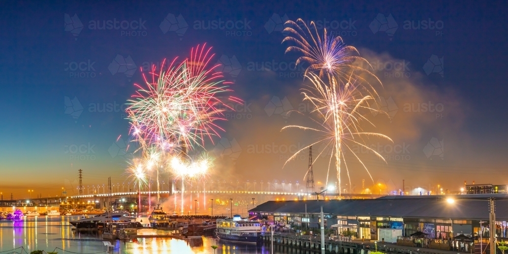 Image of Fireworks going off in a twilight sky over a city marina ...