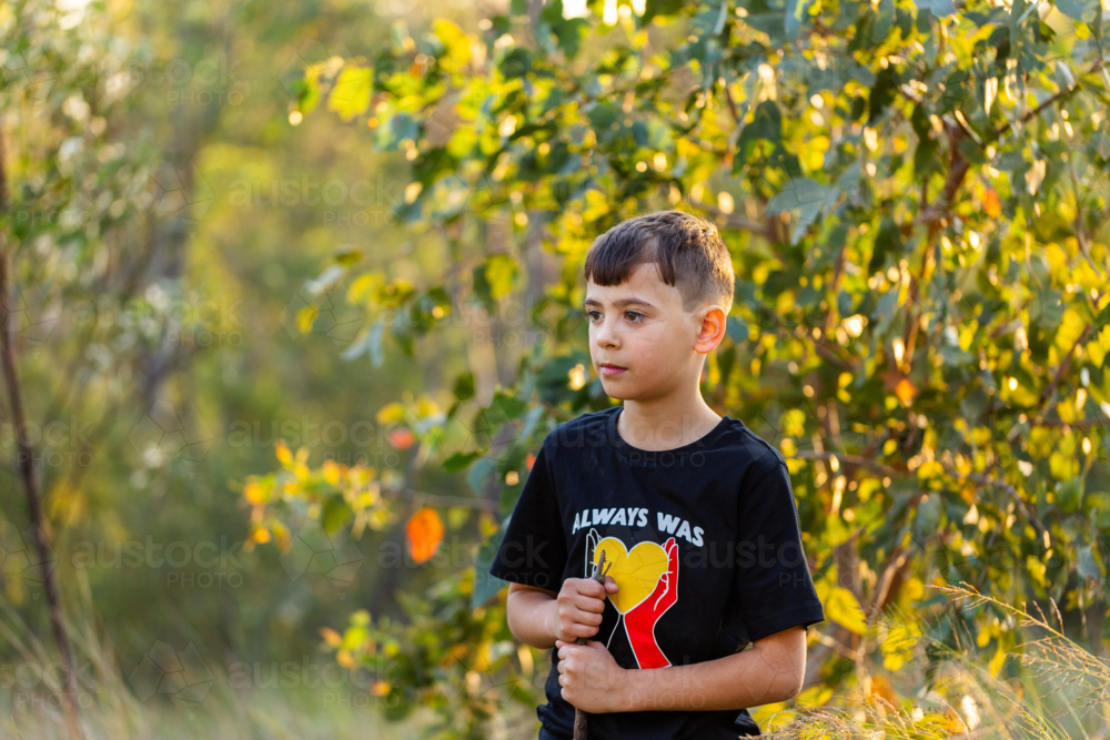 Image of First Nations Australian boy playing outside in bushland with ...