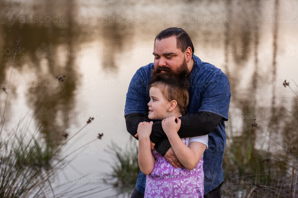 Image of First Nations Australian father hugging young daughter beside ...