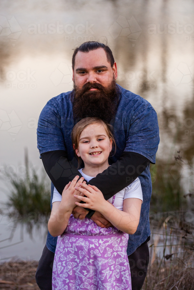 Image of First Nations Australian father hugging young daughter beside ...