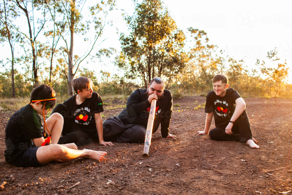 Image of First Nations Australian man with his kids sitting in bushland ...