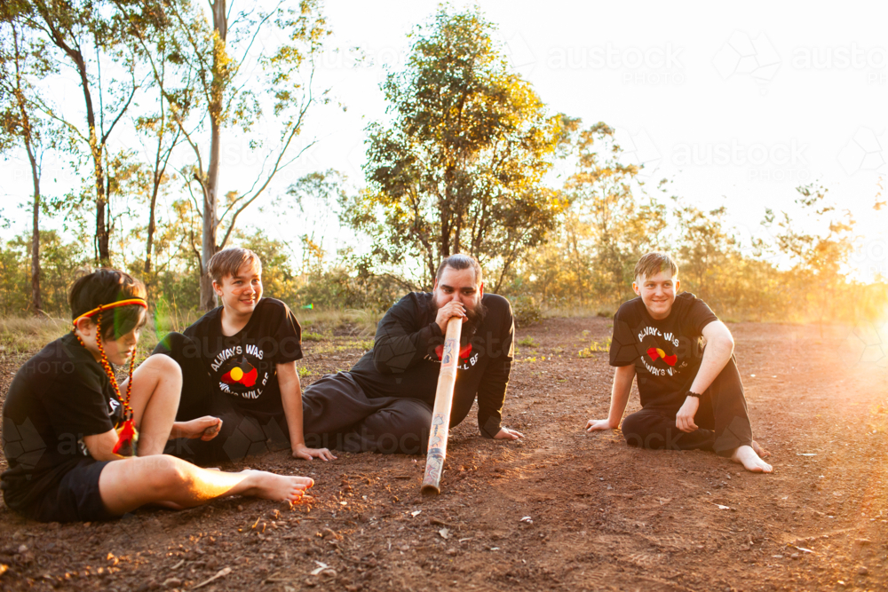 Image of First Nations Australian man with his kids sitting in bushland ...