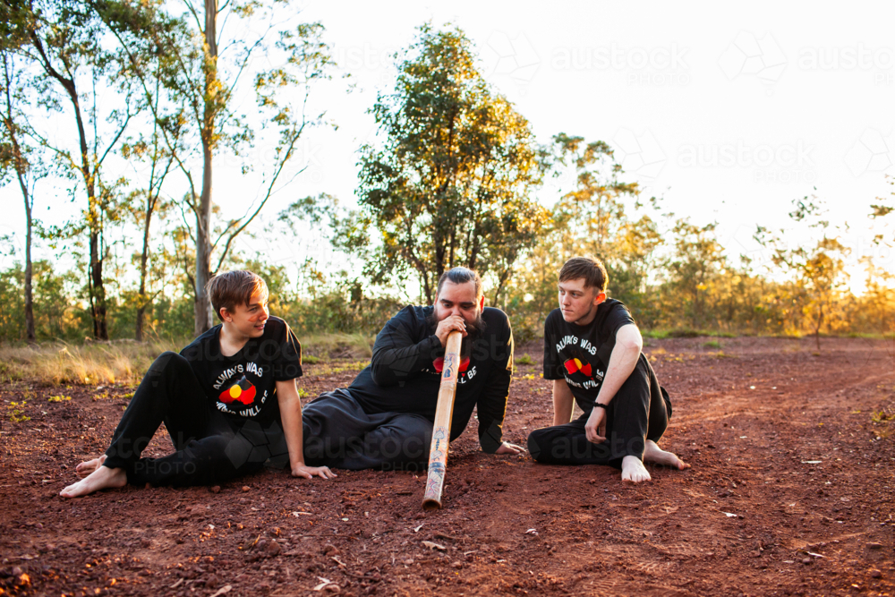 Image of First Nations Australian man with his kids sitting in bushland ...