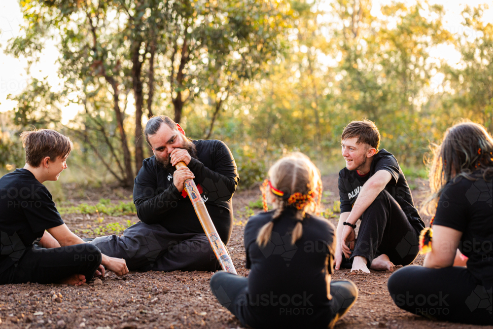 Image of First Nations Australian man with his kids sitting in bushland ...