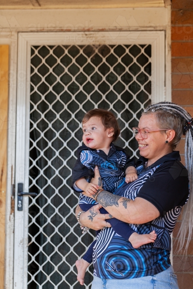 Image of First nations Australian Mum holding baby standing by front ...
