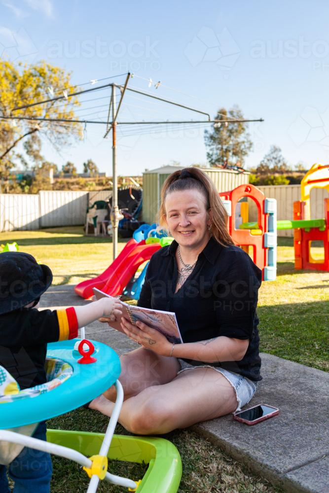 Image of First Nations Australian mum sitting in backyard writing in ...