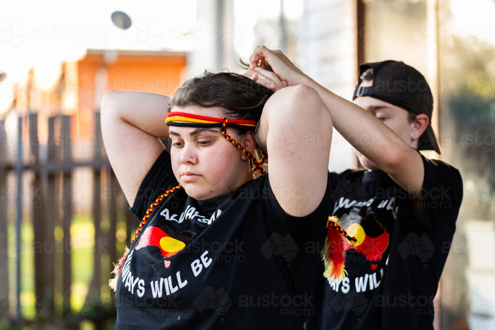 Image of First Nations Australian teenager tying on cultural coloured ...
