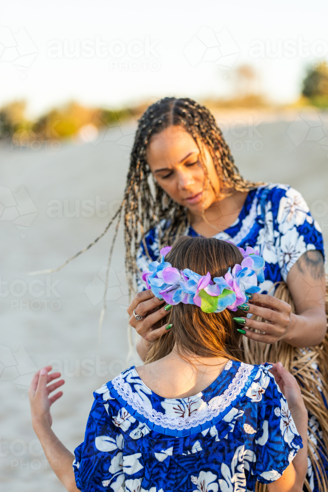 Image of First Nations Australian Torres Strait Islander mother dressing daughter for cultural ...