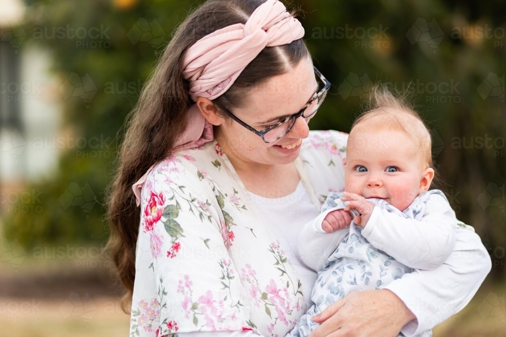 Image of five month old baby outside cuddling with smiling mother ...
