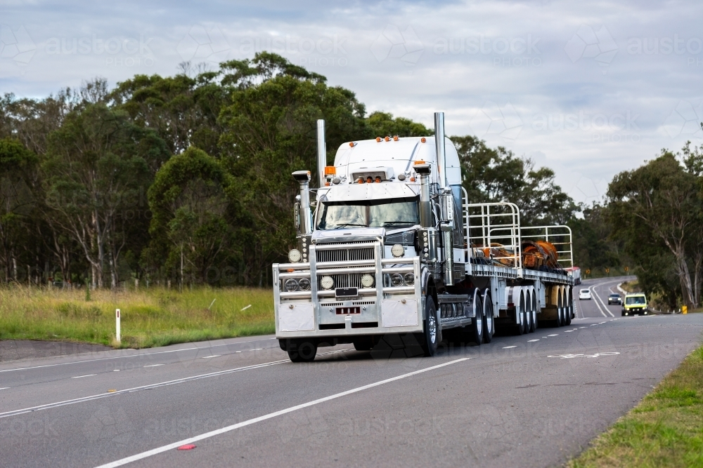 Image of flatbed truck driving down rural road - Austockphoto