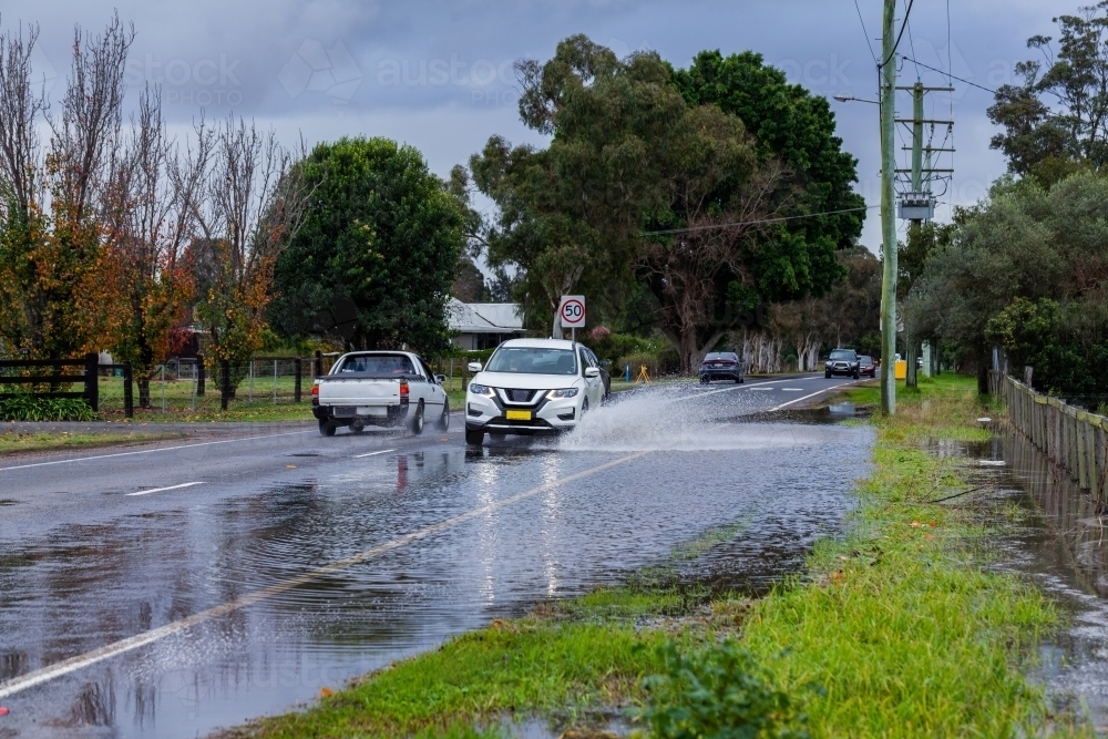 Image of Flood water forming puddle on highway road through town with ...