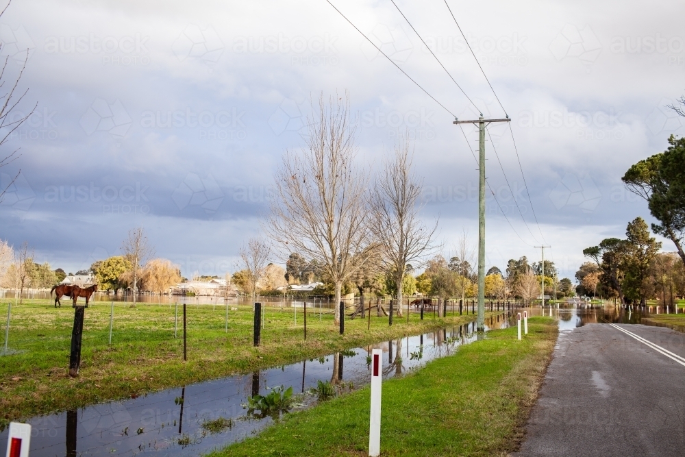 Image of Flood water in paddock beside road at edge of town - Austockphoto