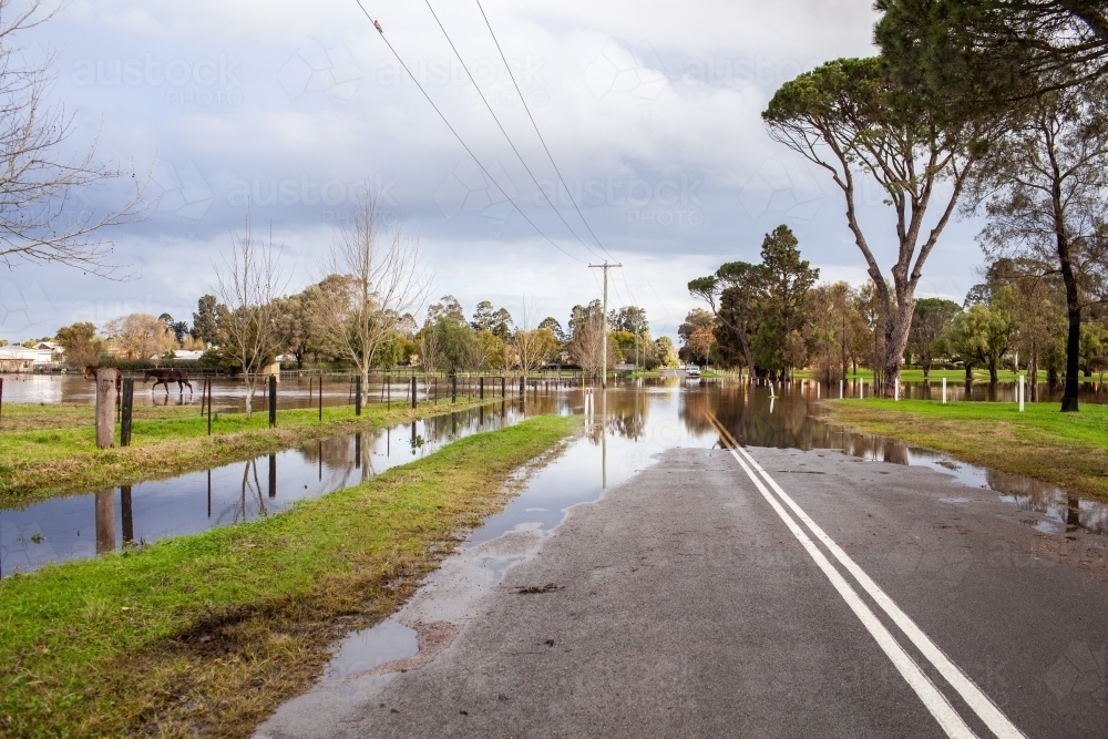 Image of Flood water in paddock beside road at edge of town - Austockphoto