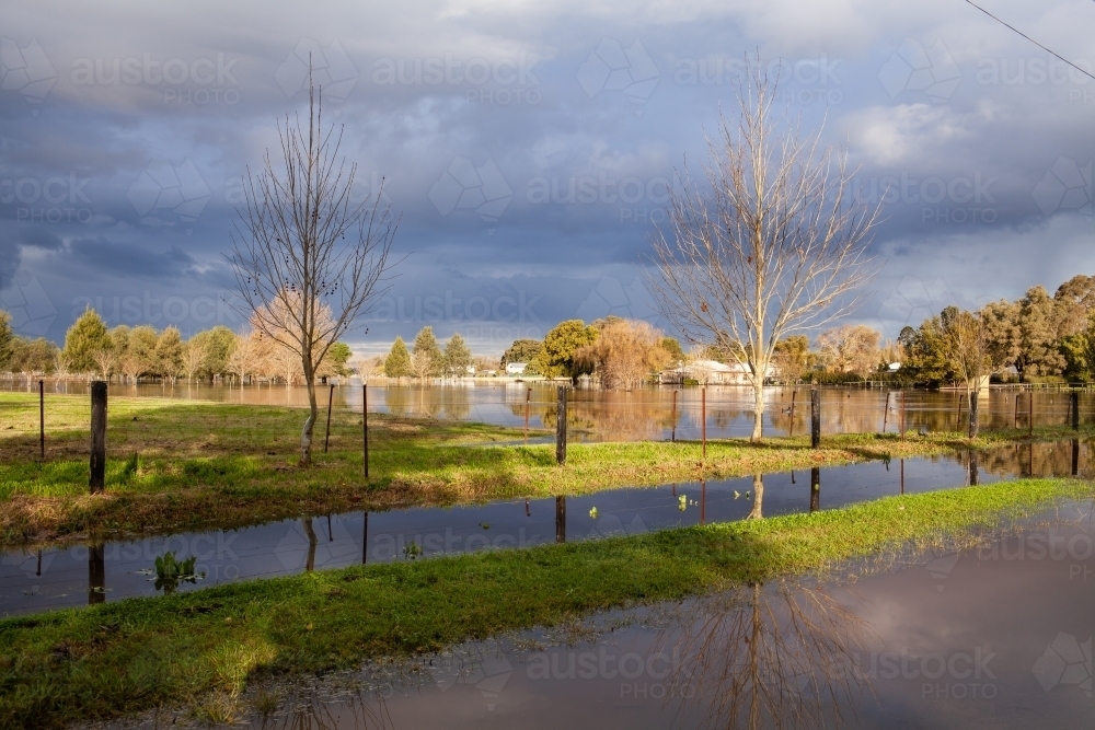 Image of Flood water in paddock beside road at edge of town - Austockphoto
