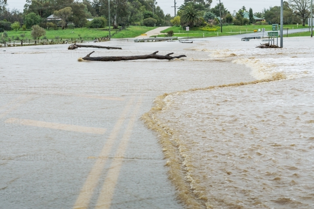 Image of Flood waters and debris rushing over a highway - Austockphoto