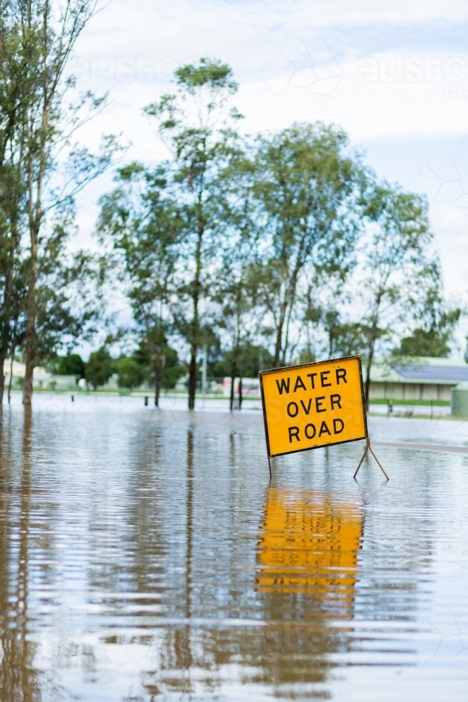 Image of Floodwater rising over water over road sign on highway ...