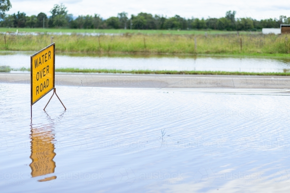 Image of Floodwater rising over water over road sign on highway ...
