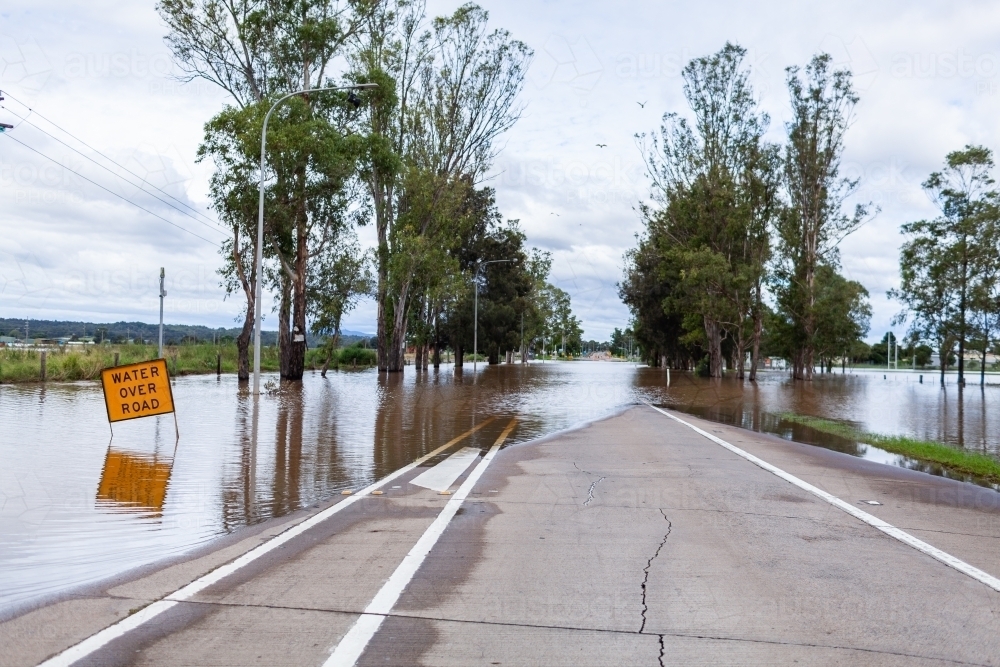 Image of Floodwater rising over water over road sign on highway ...