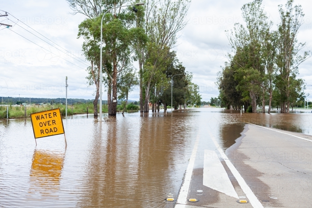 Image of Floodwater rising over water over road sign on highway ...