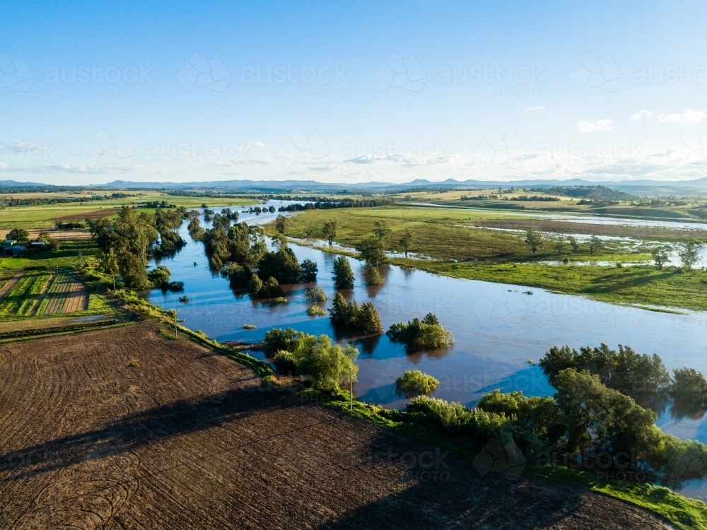 Image of Floodwaters of river rising up and flooding over farmland ...