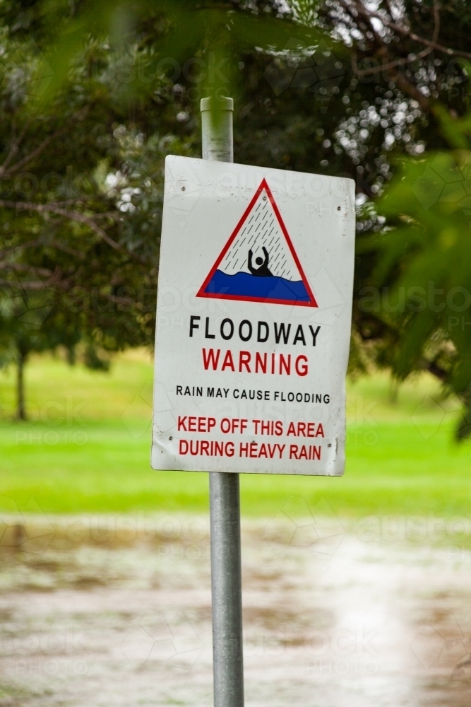 Image of Floodway warning sign with rising water behind on rainy day ...