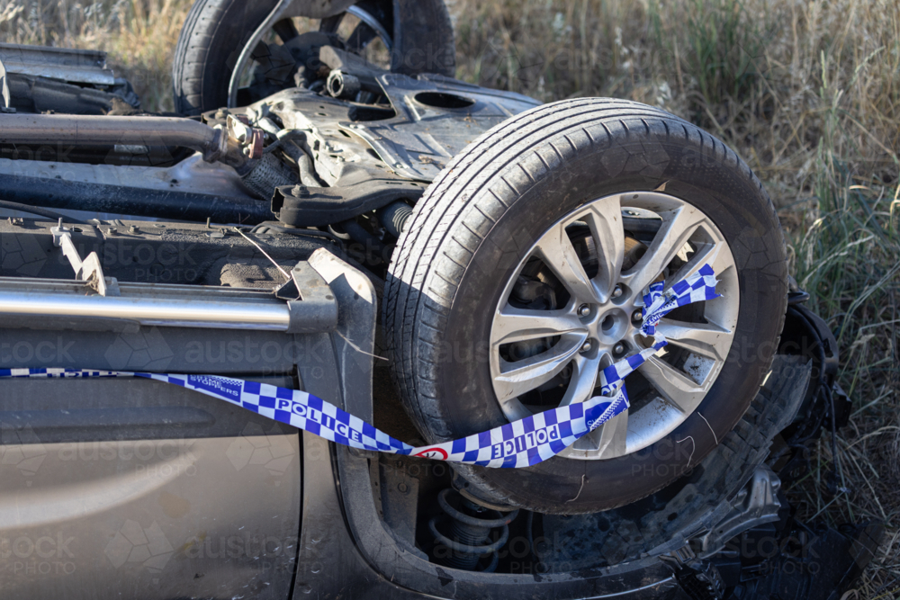 Image of focus on front wheels and police tape on overturned car ...