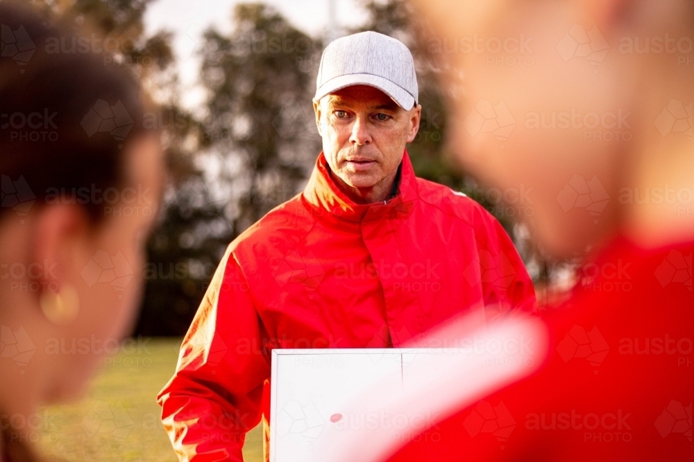 Image of Football coach explaining strategy to his team of tween girls ...