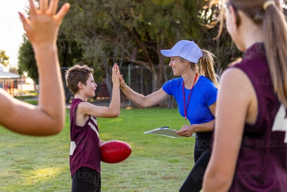 Image of football coach giving high five to schoolboy at training ...
