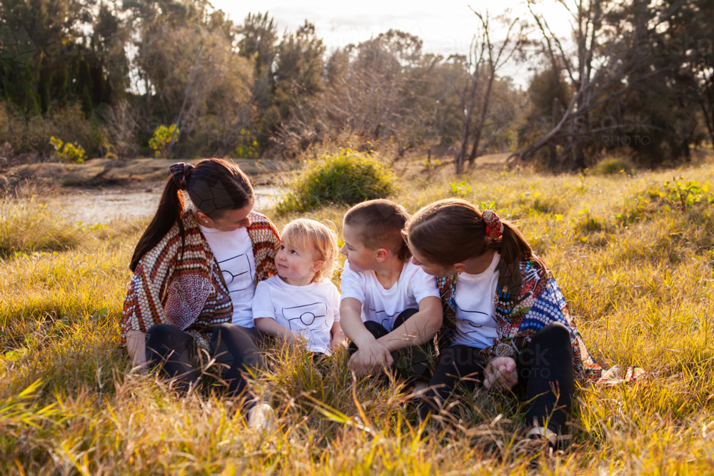 Image of Four aboriginal siblings sitting together in wild grassy area ...