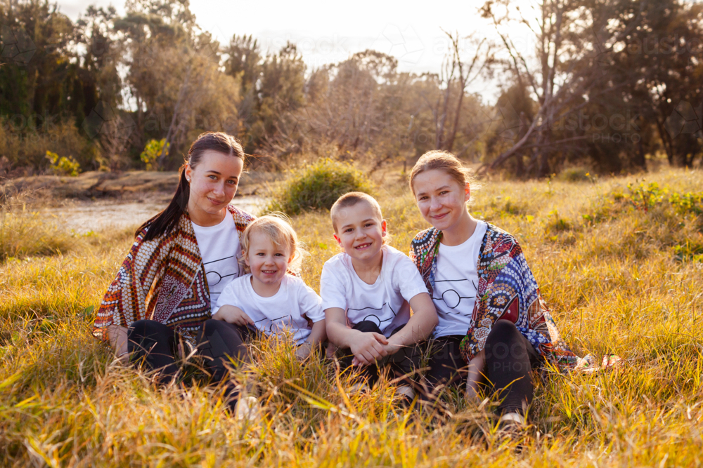 Image of Four aboriginal siblings sitting together in wild grassy area ...