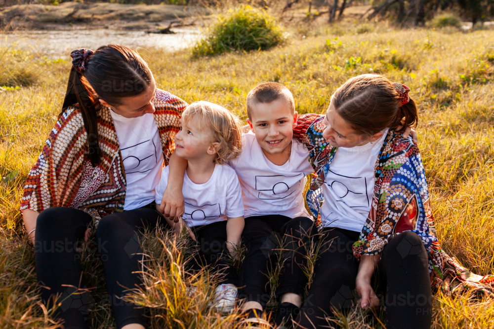 Image of Four aboriginal siblings sitting together in wild grassy area ...