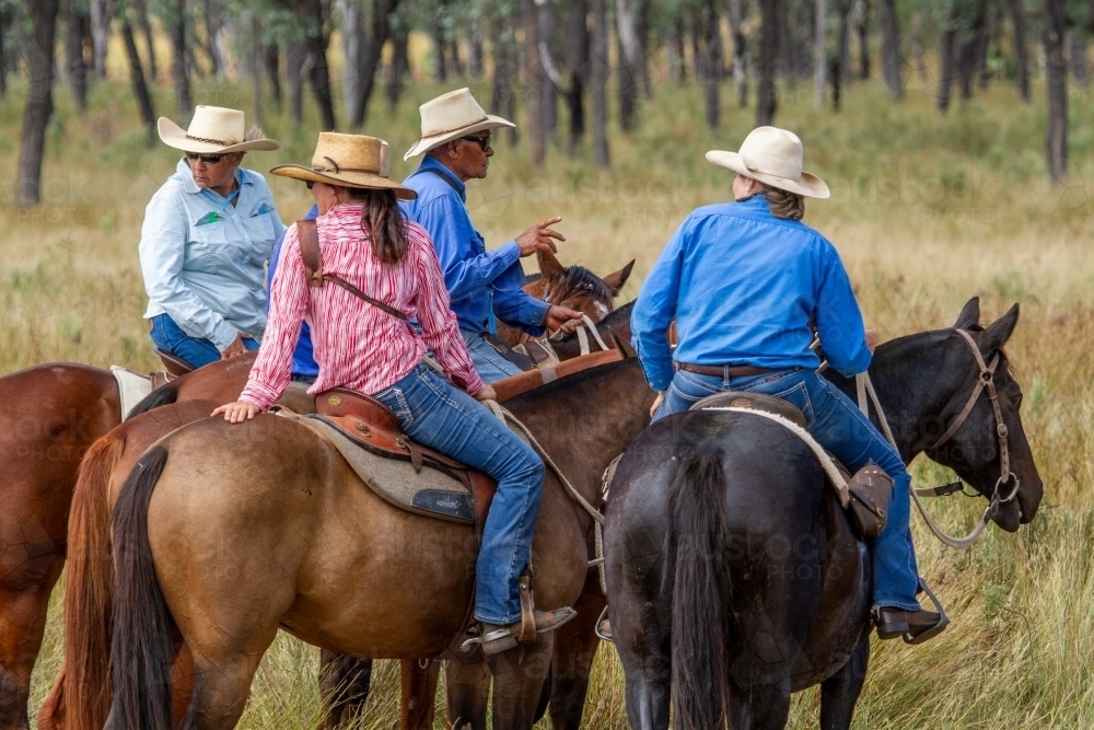 Image of Four country folk chatting on their horses. - Austockphoto