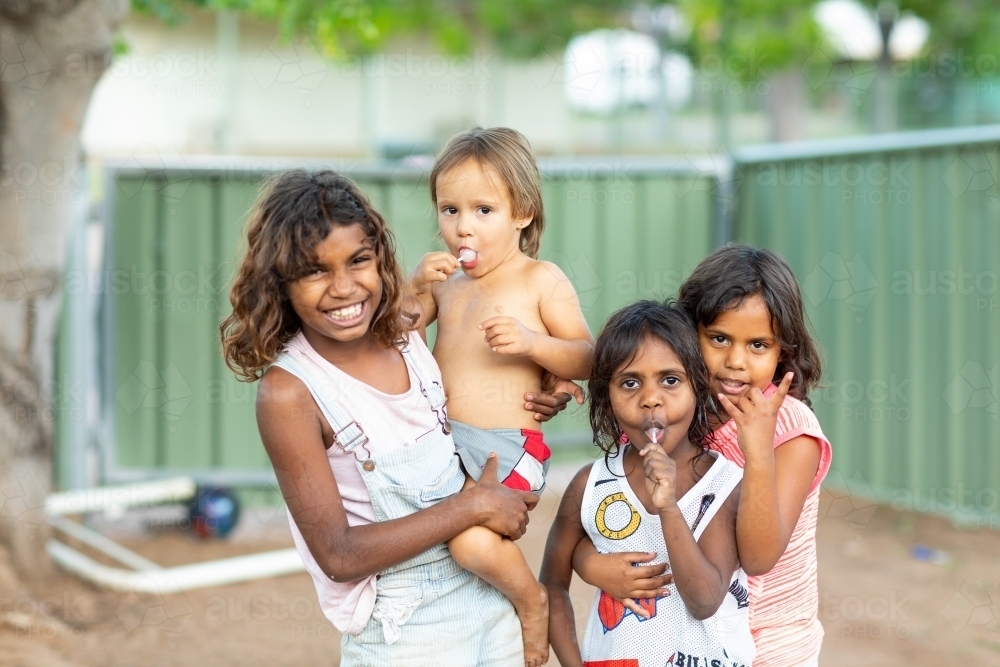 Image of four little kids with lollipops in the backyard - Austockphoto