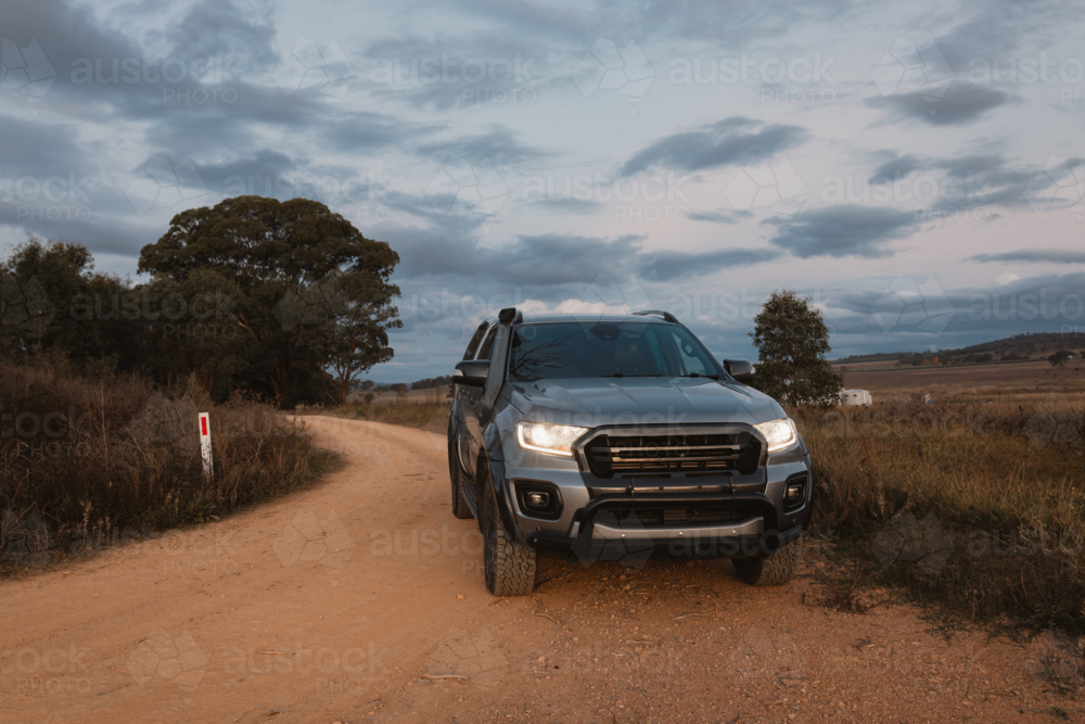 Image of Four wheel drive vehicle stopped along country road at dusk ...
