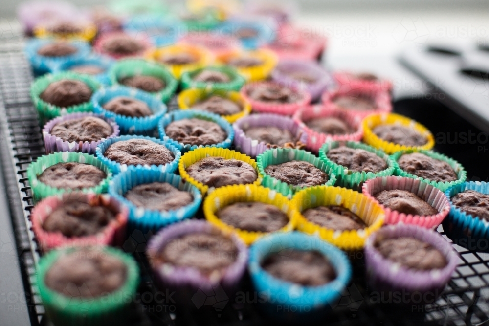 Image of freshly baked cupcakes cooling on a wire rack - Austockphoto