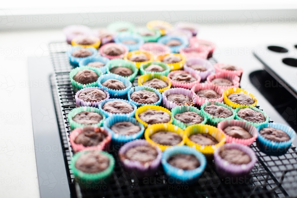 Image of freshly baked cupcakes in colourful patty cases cooling on a ...