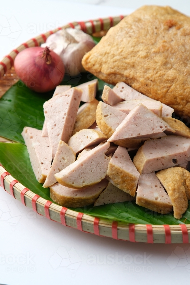 Image of Fried Cha Lua served on a banana leaf inside a woven basket ...