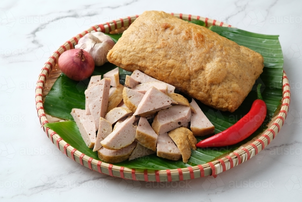 Image of Fried Cha Lua served on a banana leaf inside a woven basket ...