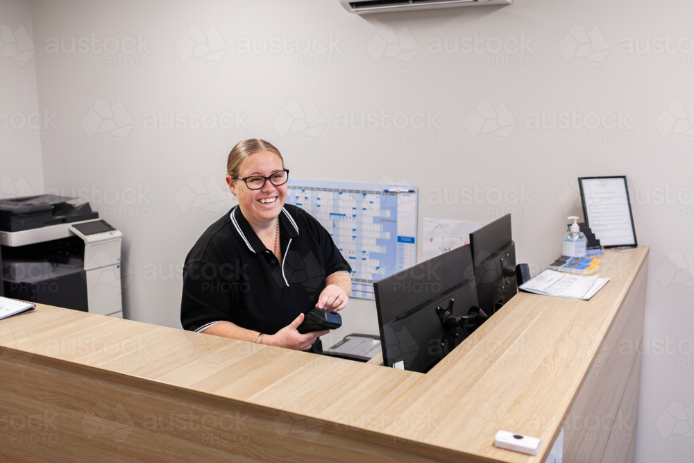 Image of front desk lady laughing while holding out payment terminal at ...