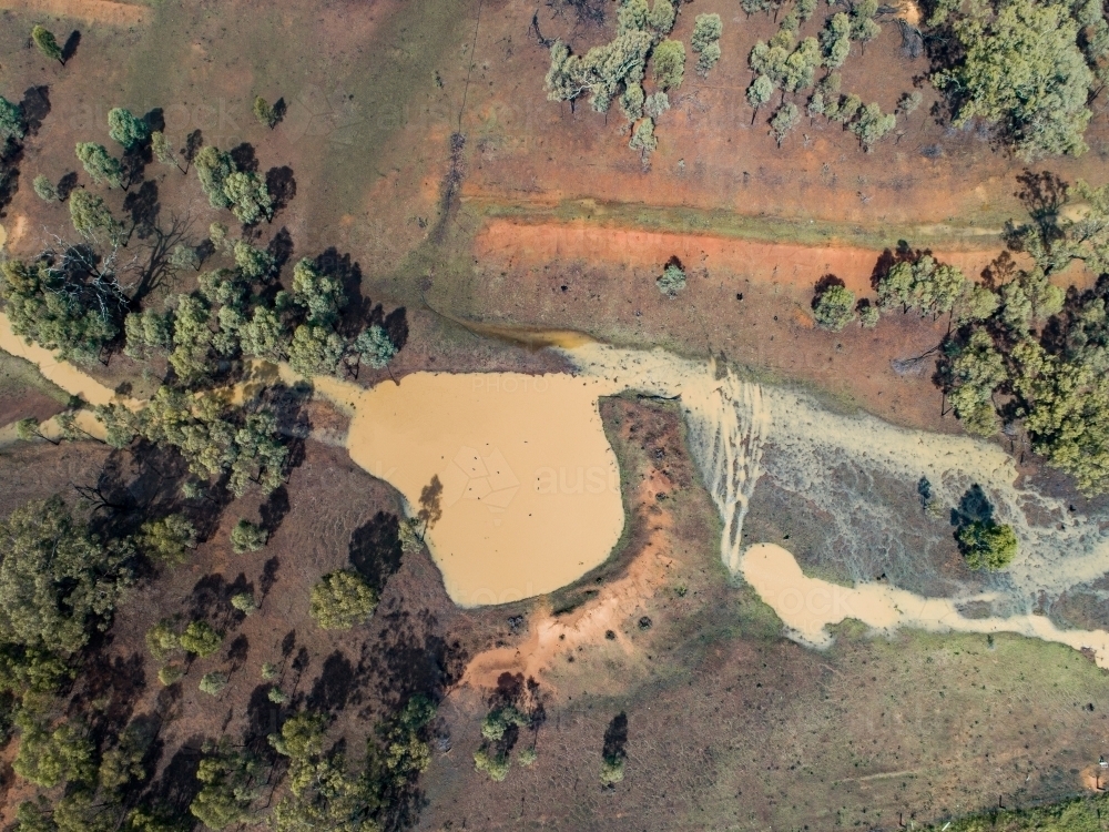 Image of Full creek and overflowing dam in rural paddock - Austockphoto