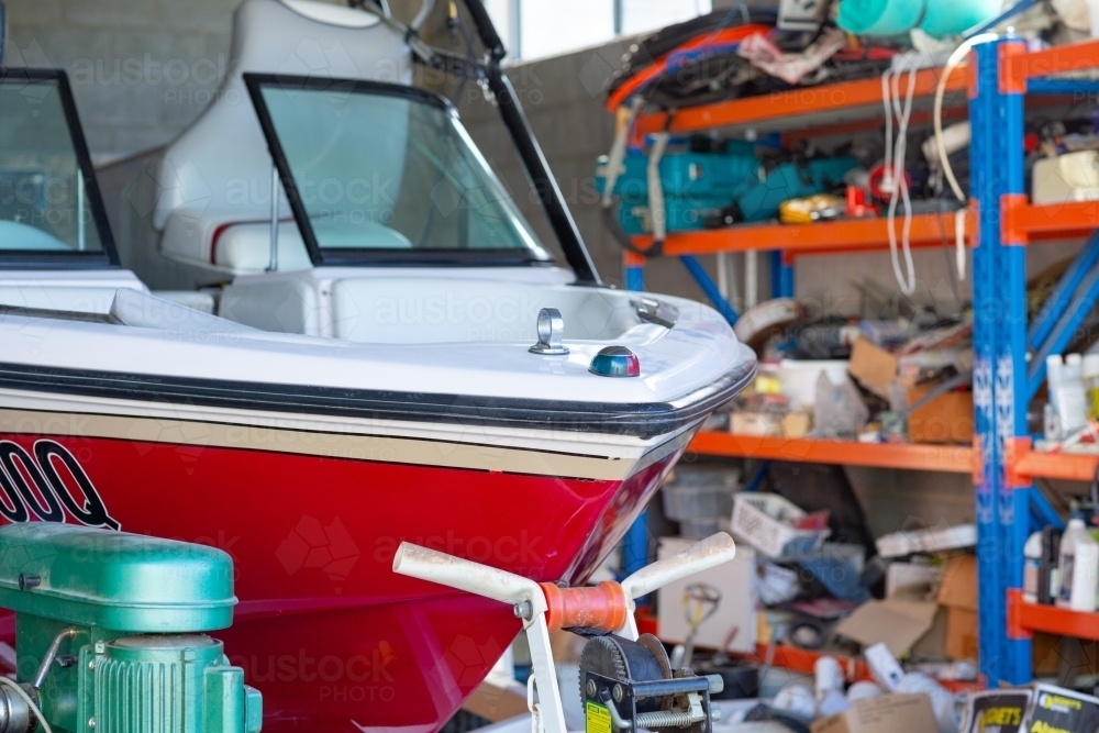 Image of garage full of boat and shelving with lots of stuff - Austockphoto