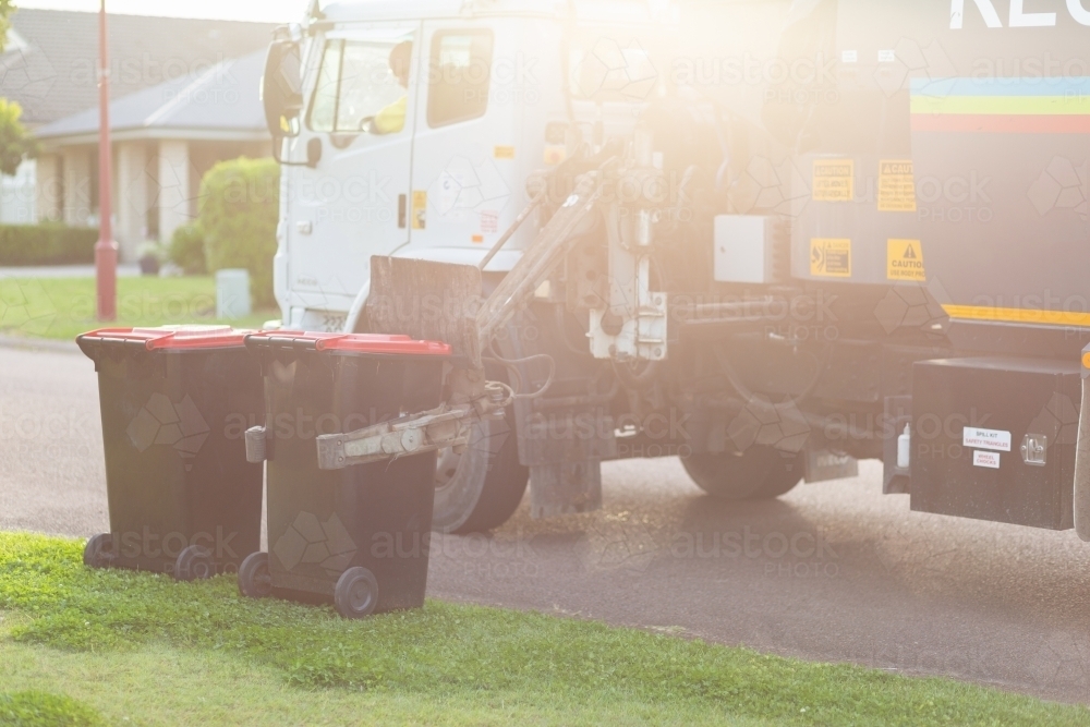 Image of Garbage truck picking up bins from curb side in suburban area ...