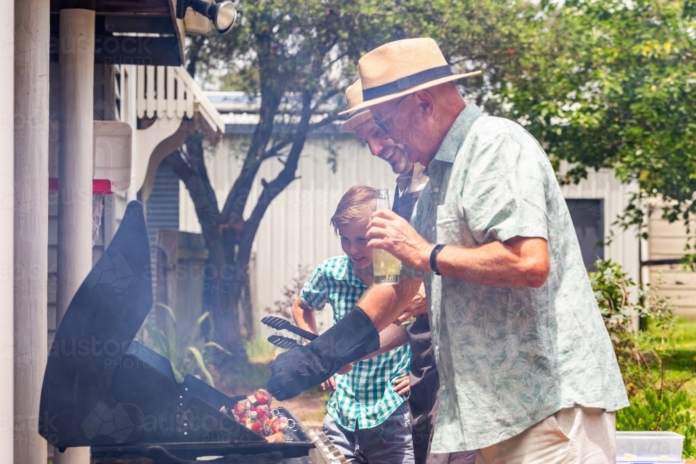 Image of Generations of men cooking barbeque together at family ...