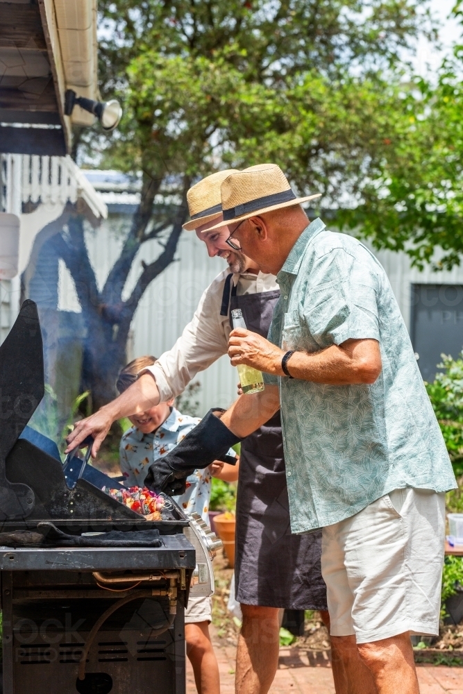Image of Generations of men cooking barbeque together at family ...