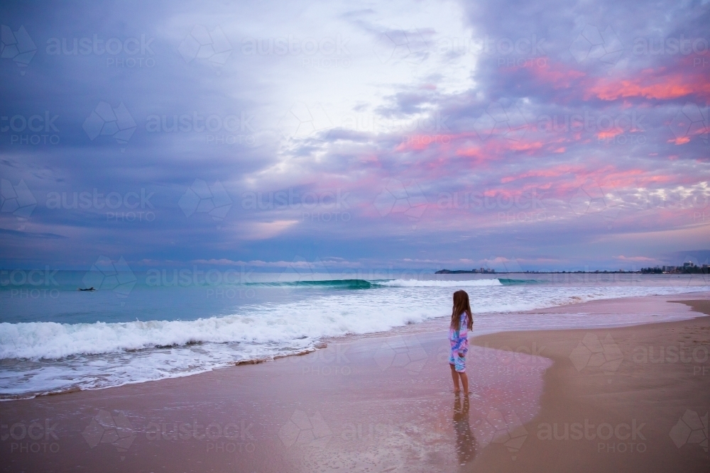 Image of girl at the beach at dusk looking at the ocean - Austockphoto