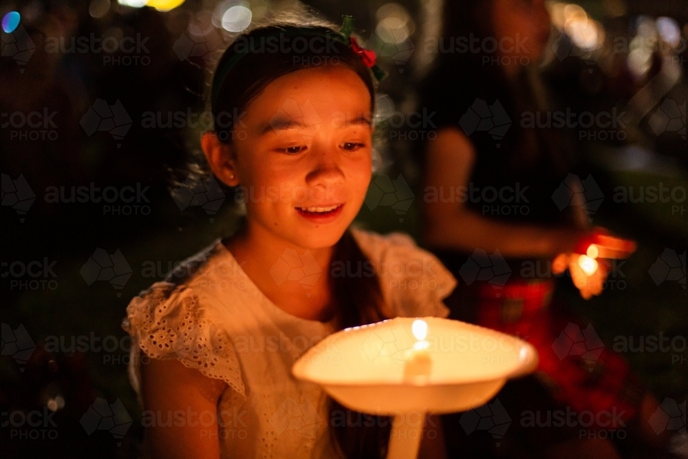 Image of girl holding a candle at a community carols event - Austockphoto