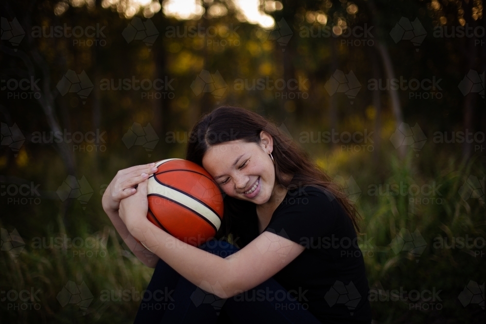 Image of girl hugging basketball - Austockphoto