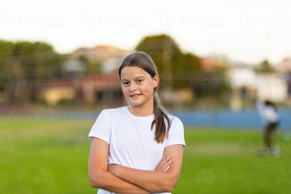 Image of girl in white tee with arms crossed showing slight smile and ...